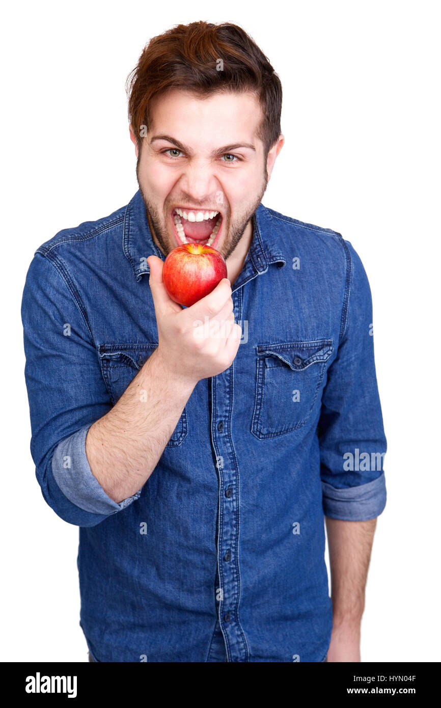 Portrait of a young man eating fresh apple on isolated white background ...