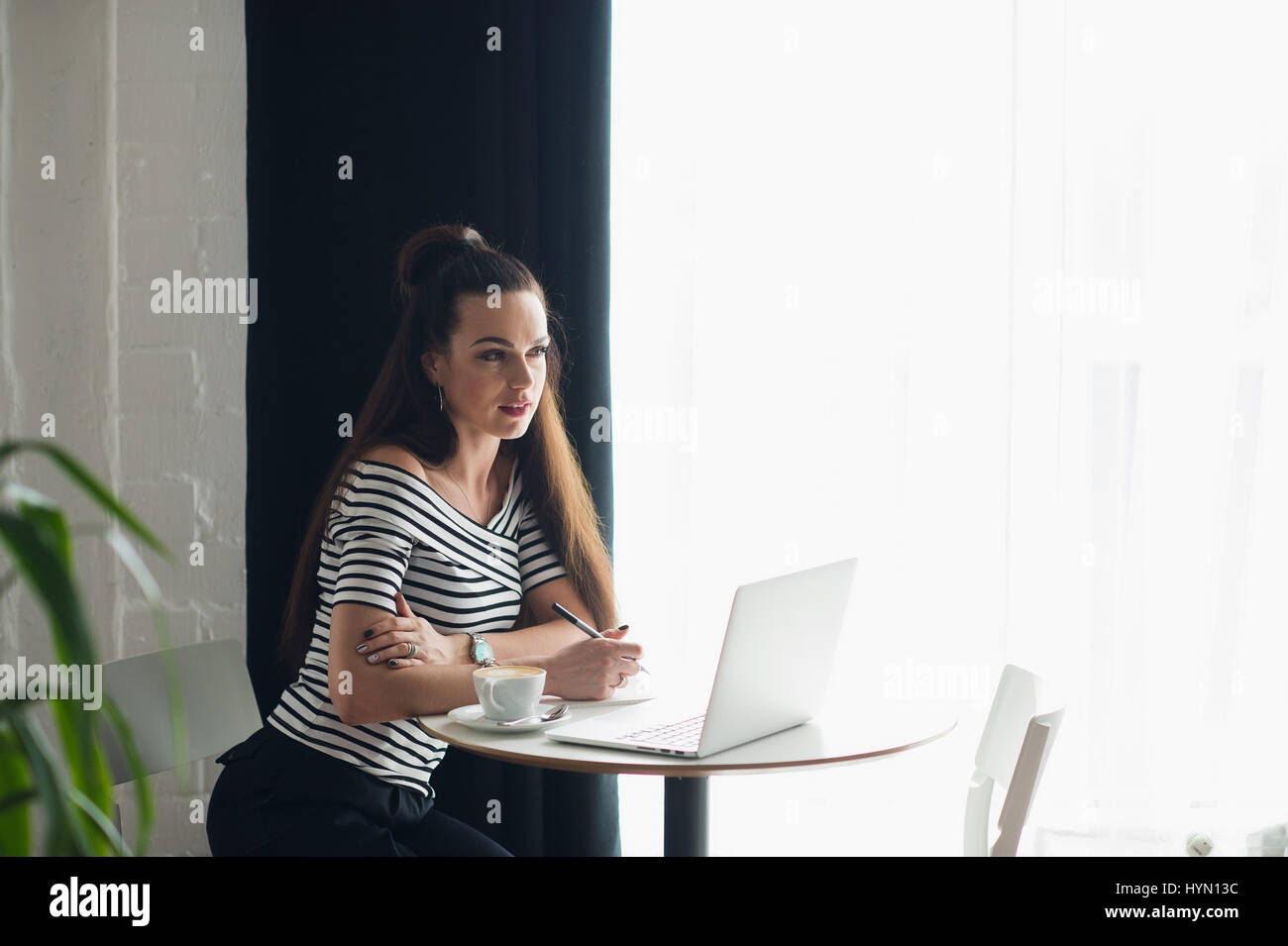 Young woman writer working at the cafe with notebook and laptop ...