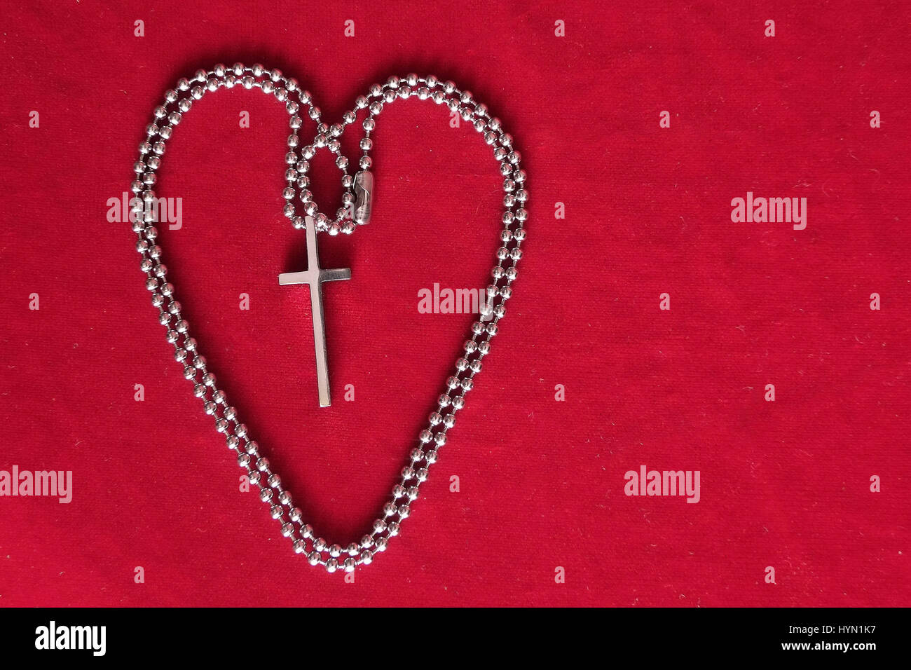 Small christian cross in a heart shaped chain Stock Photo - Alamy