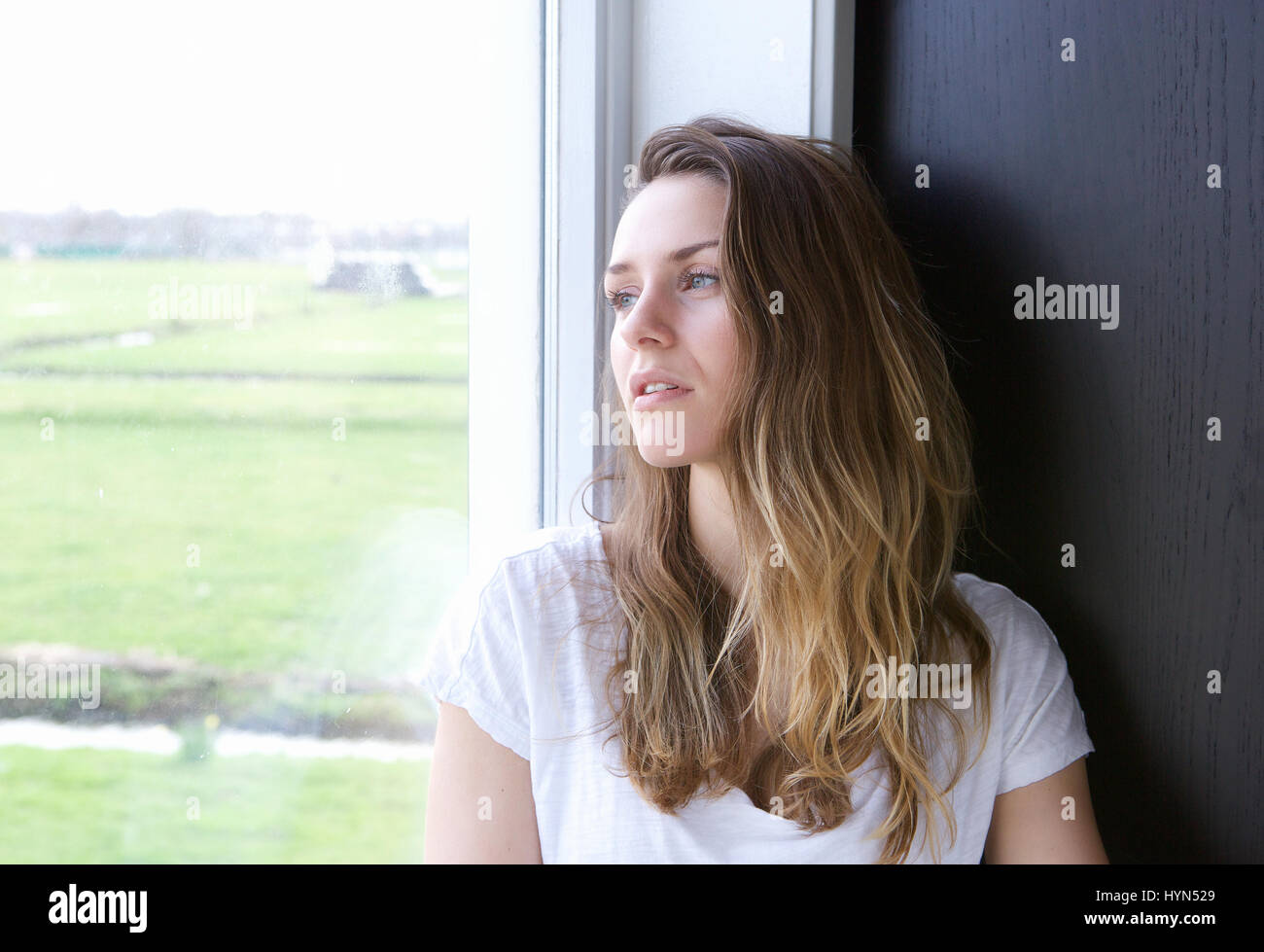 Close up portrait of a young woman looking outside through window Stock ...