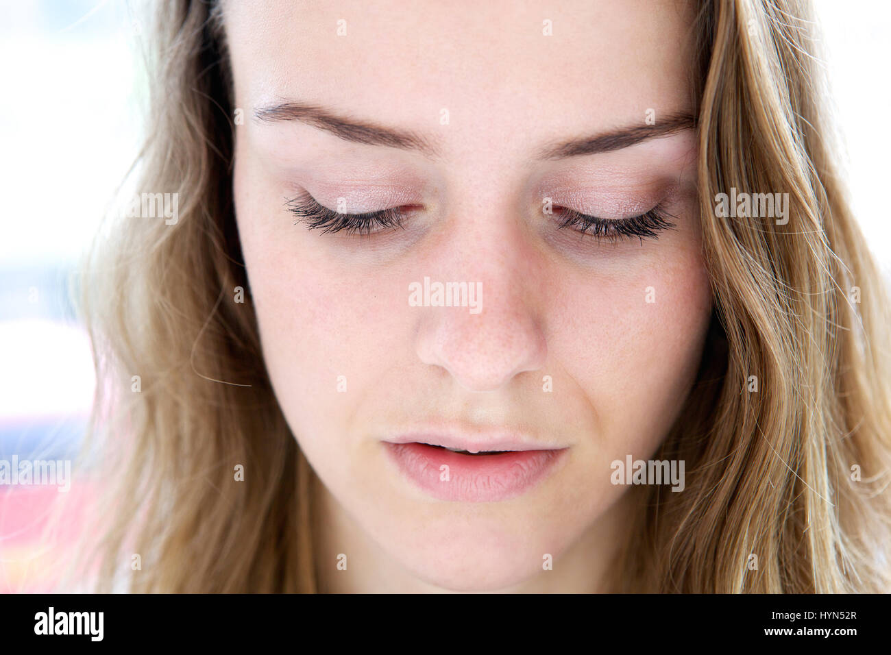 Horizontal close up portrait of a beautiful young woman looking down ...