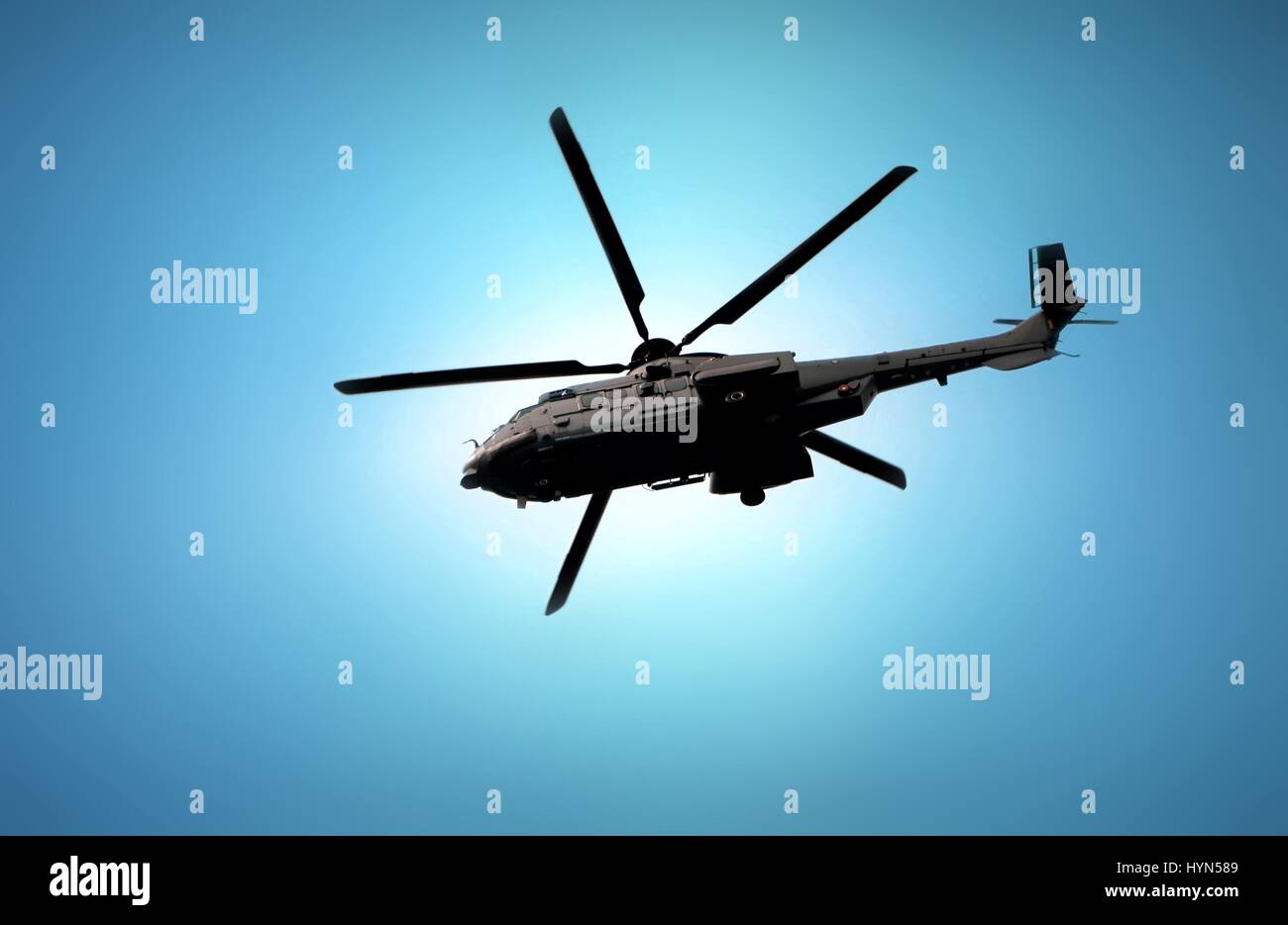 Military helicopter flying under blue sky Stock Photo - Alamy
