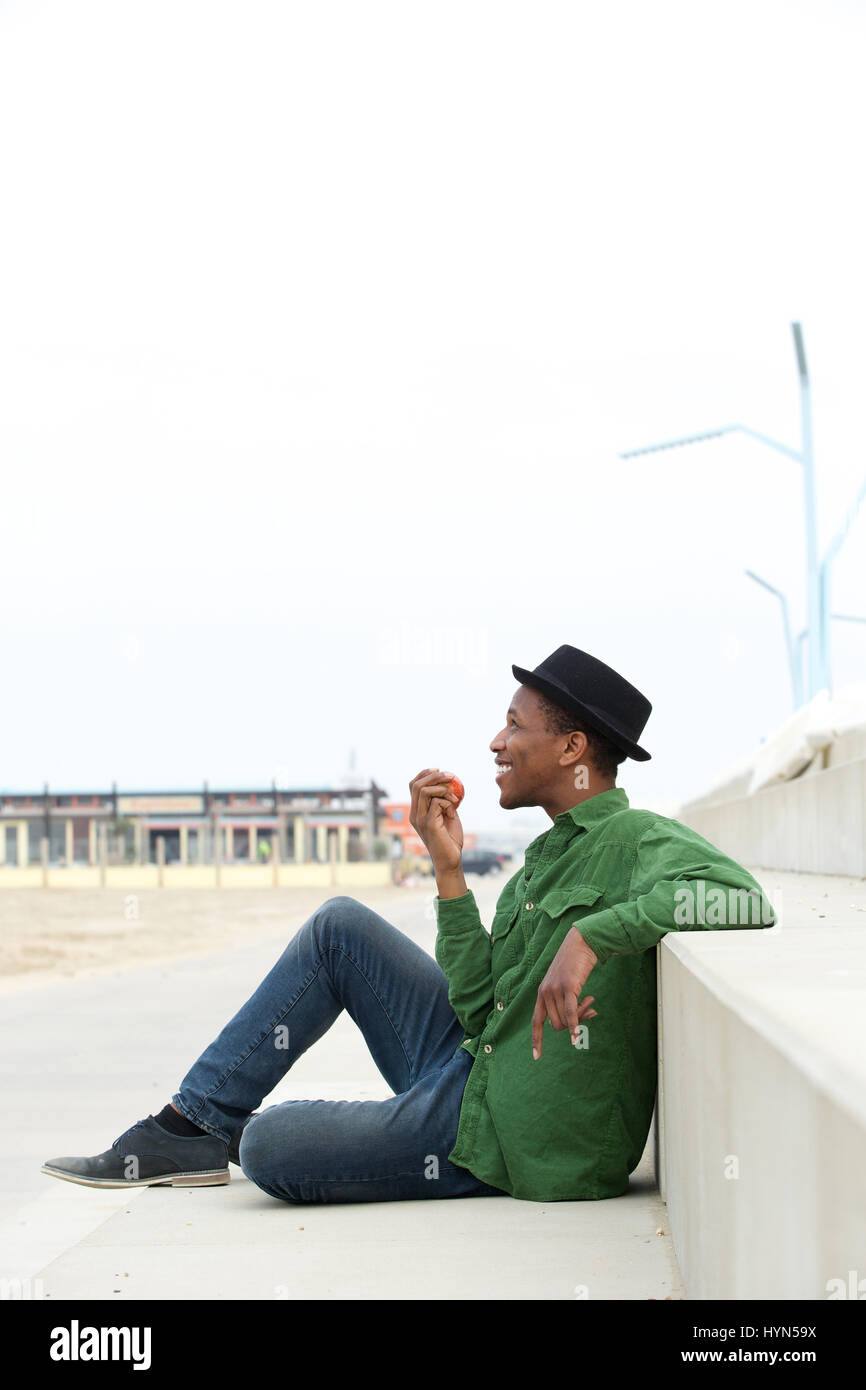 Portrait of a healthy young black man eating apple outdoors Stock Photo ...