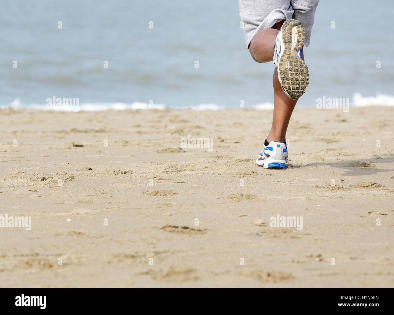Low angle rear view of young man jogging at the beach Stock Photo - Alamy