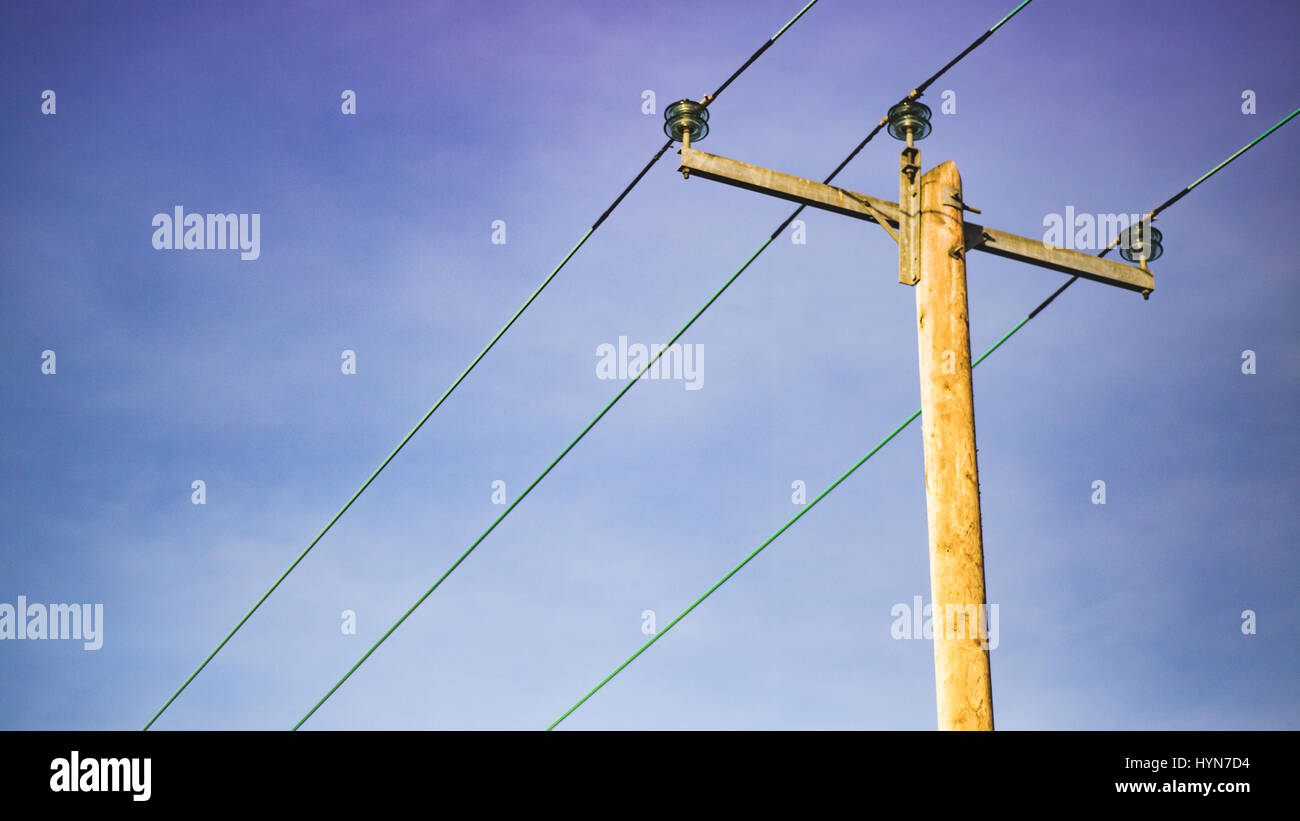 Wooden post with electrical wires on a blue sky Stock Photo - Alamy