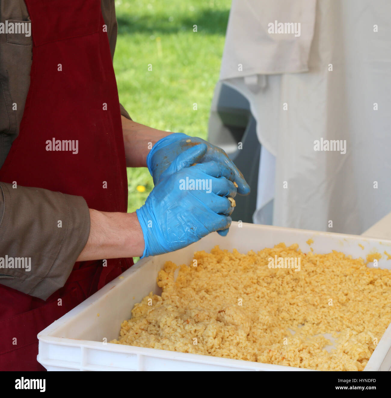 cook with blue gloves creates rice balls and then fry them in hot oil ...
