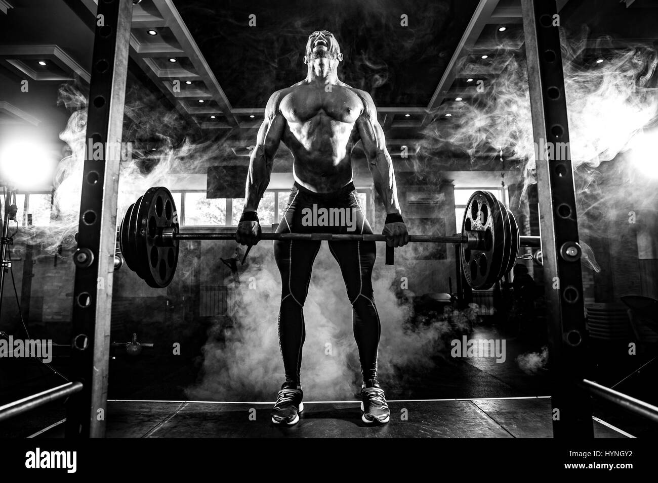 Young shirtless man doing deadlift exercise at gym. Screaming for ...