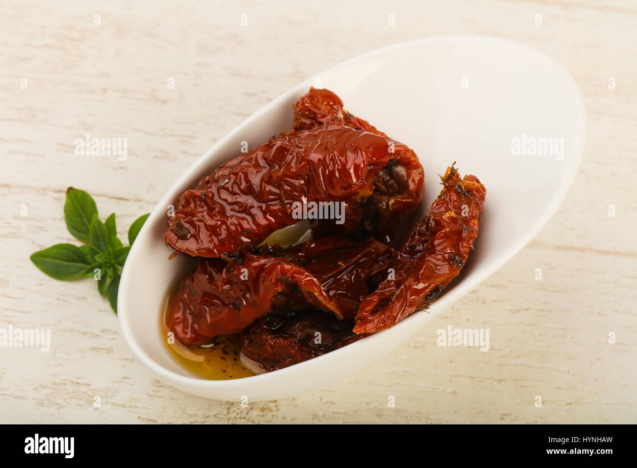 Dried tomato in olive oil with basil leaves Stock Photo - Alamy