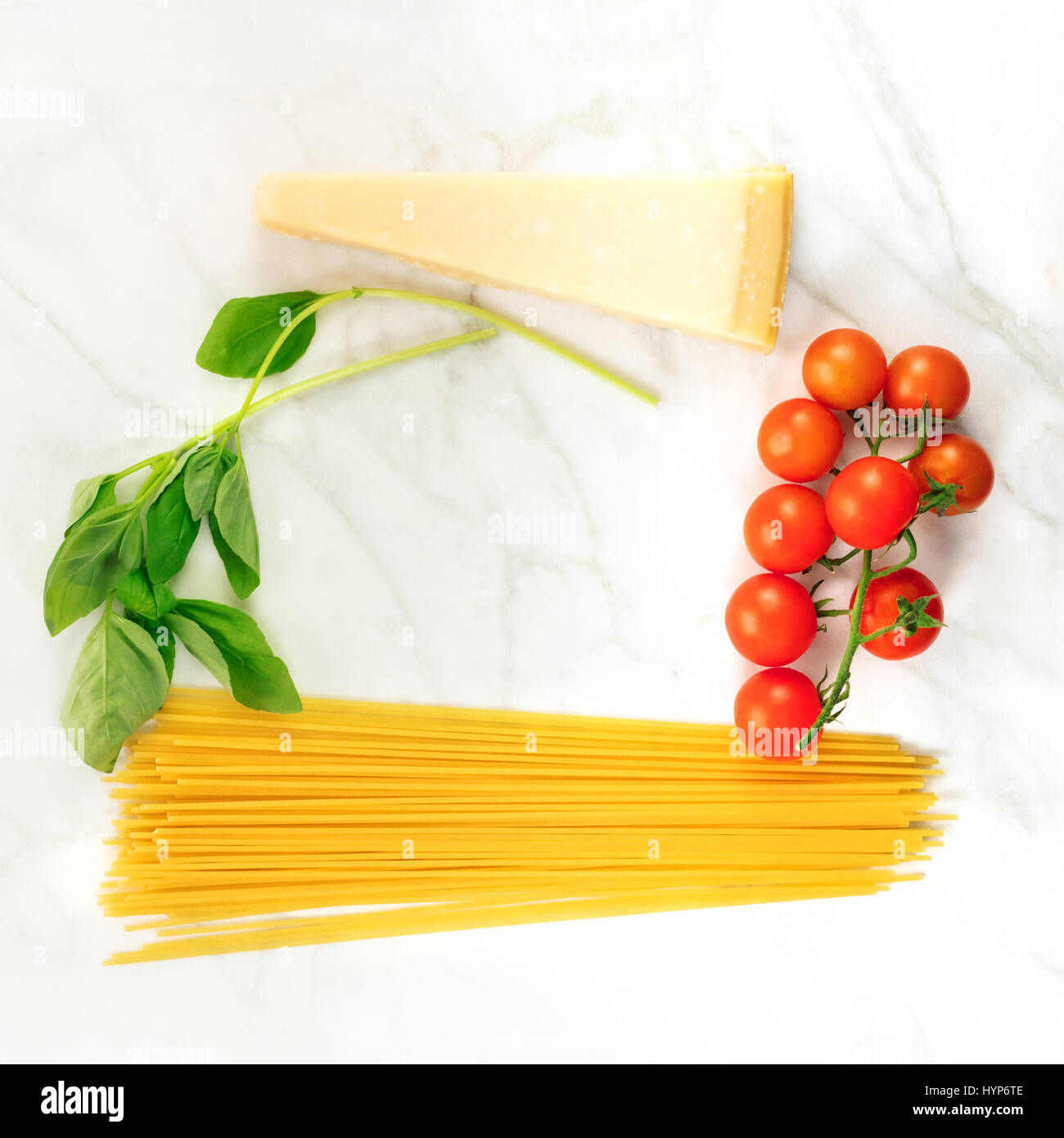An overhead photo of basic pasta ingredients on a white marble table ...