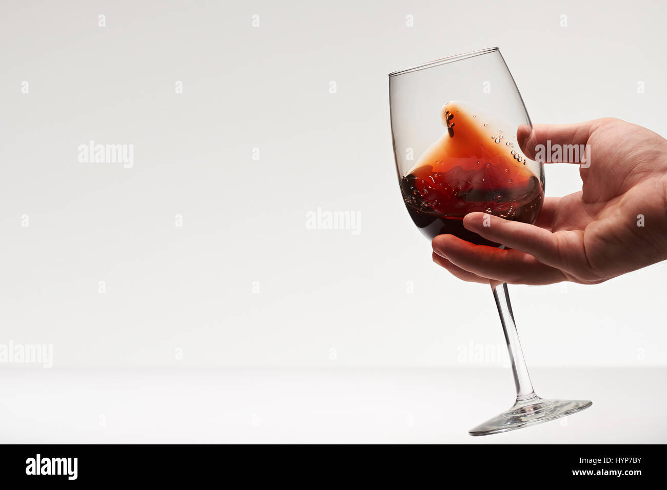 Hand shake red wine in glass close-up isolated on white background ...