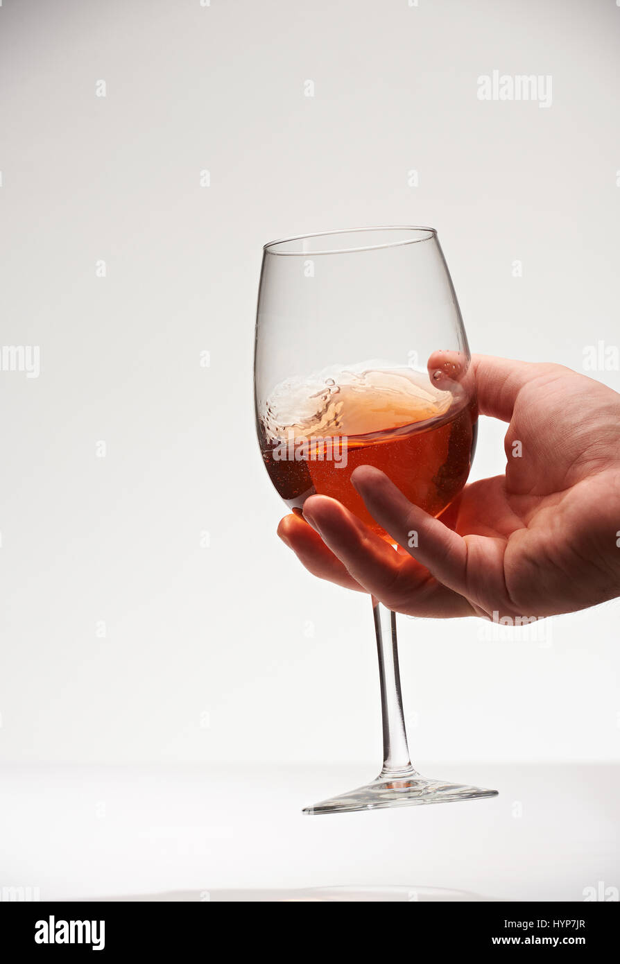 Hand shaking glass with red wine isolated on white background. Closeup ...