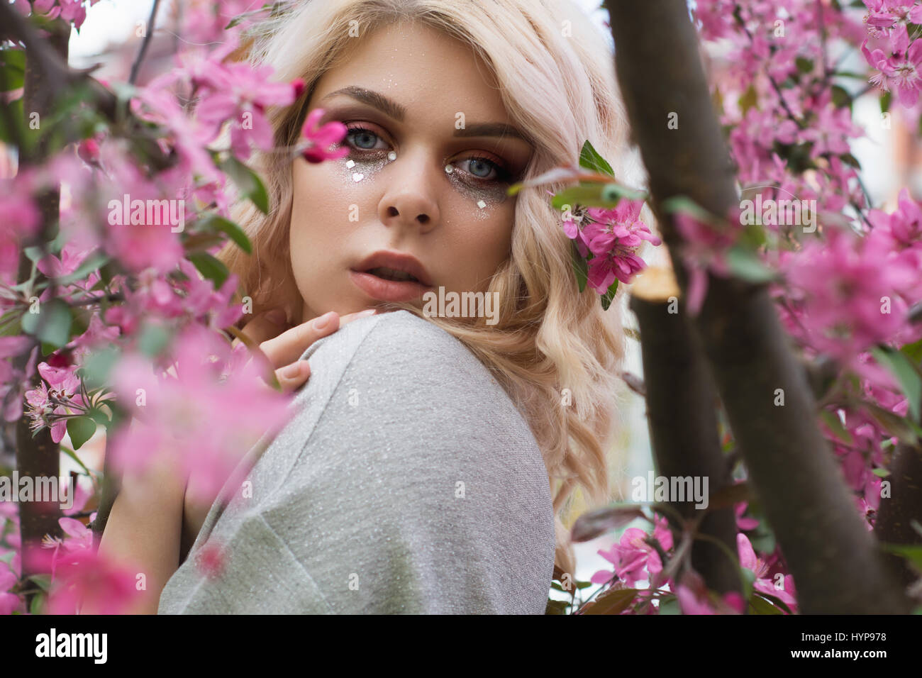 Beautiful young woman enjoying sunny day in park during cherry blossom ...
