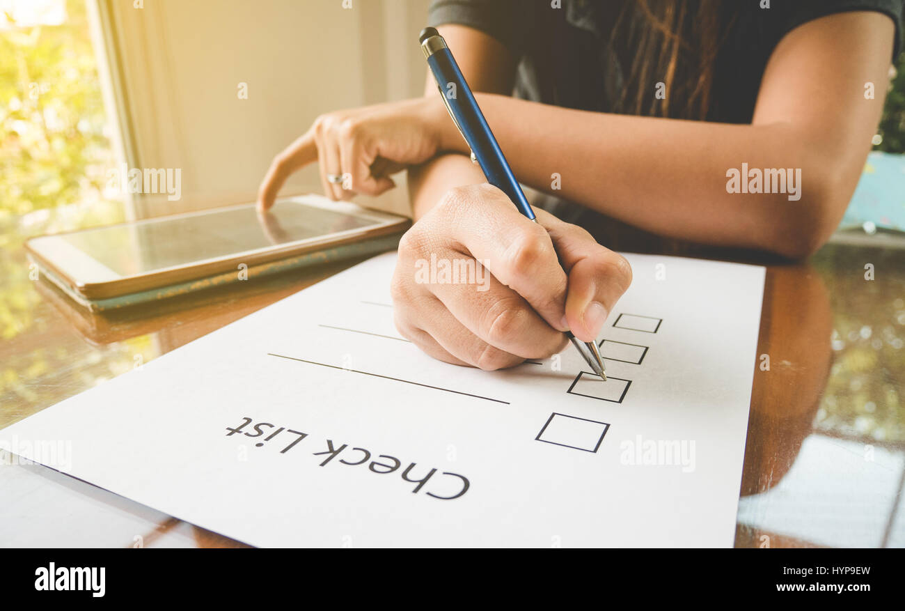 close- up hand holding pen on check list paper with tablet in Stock ...