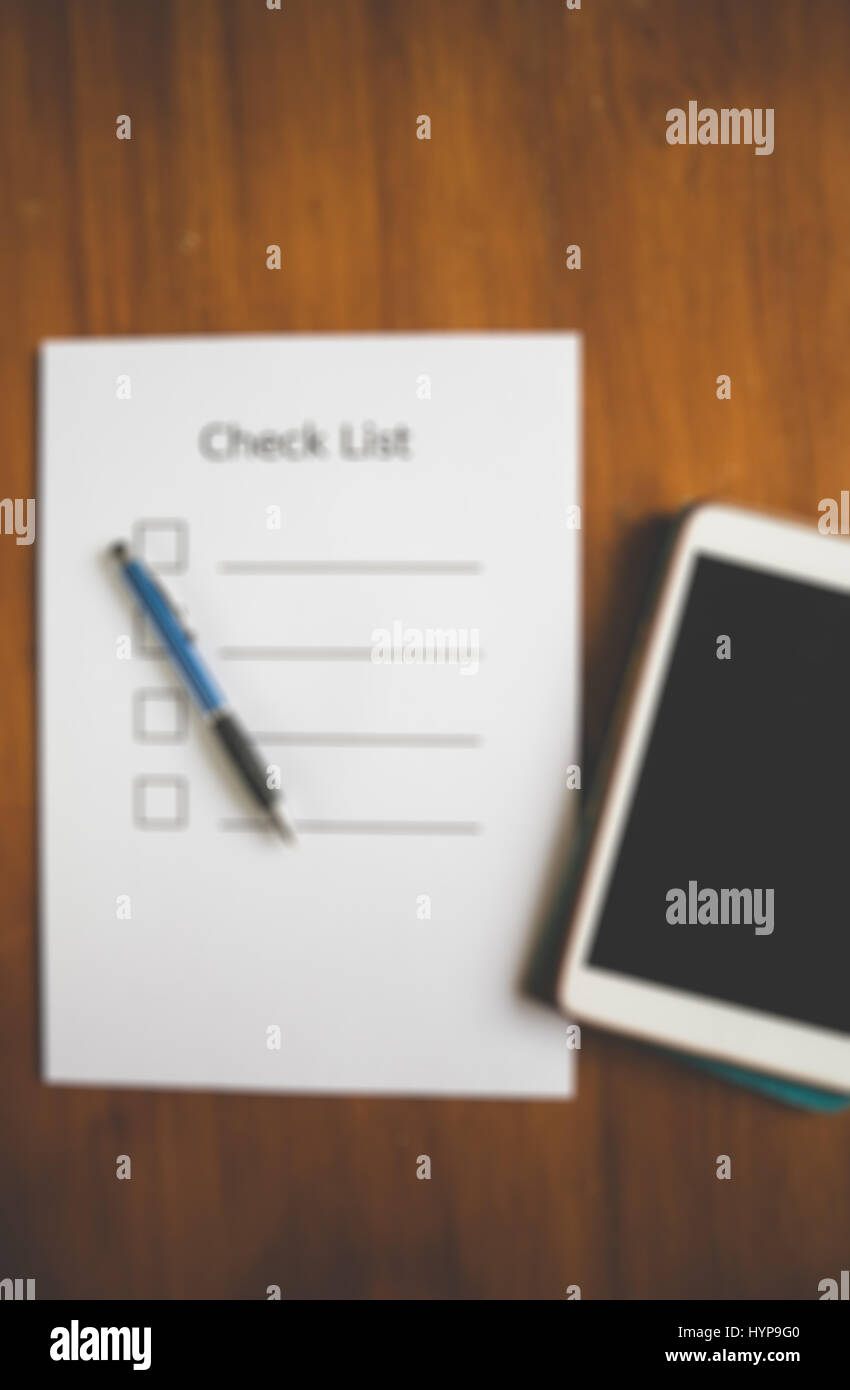 Blur background Top view of hand holding pen on check list paper with ...