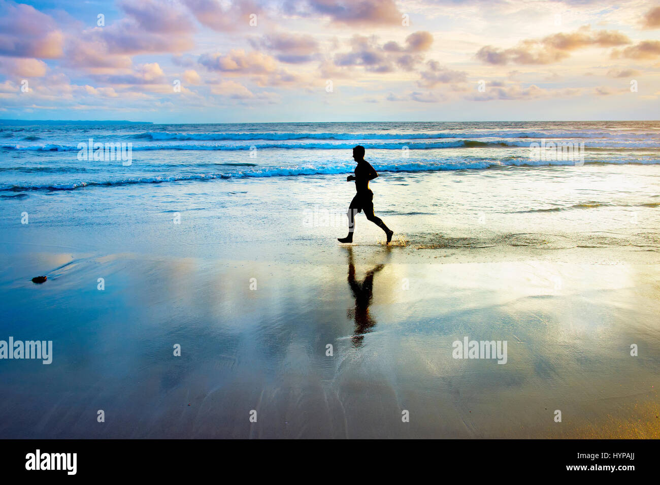 Man running on the beach at sunset. Bali island, Indonesia Stock Photo ...