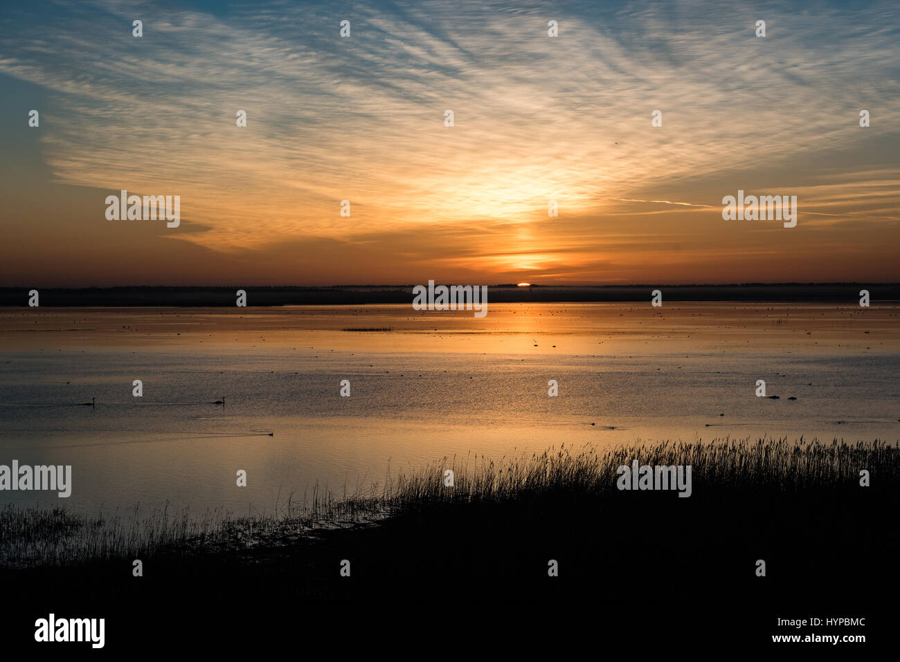 beautiful sunrise over country lake with orange clouds and reflections ...
