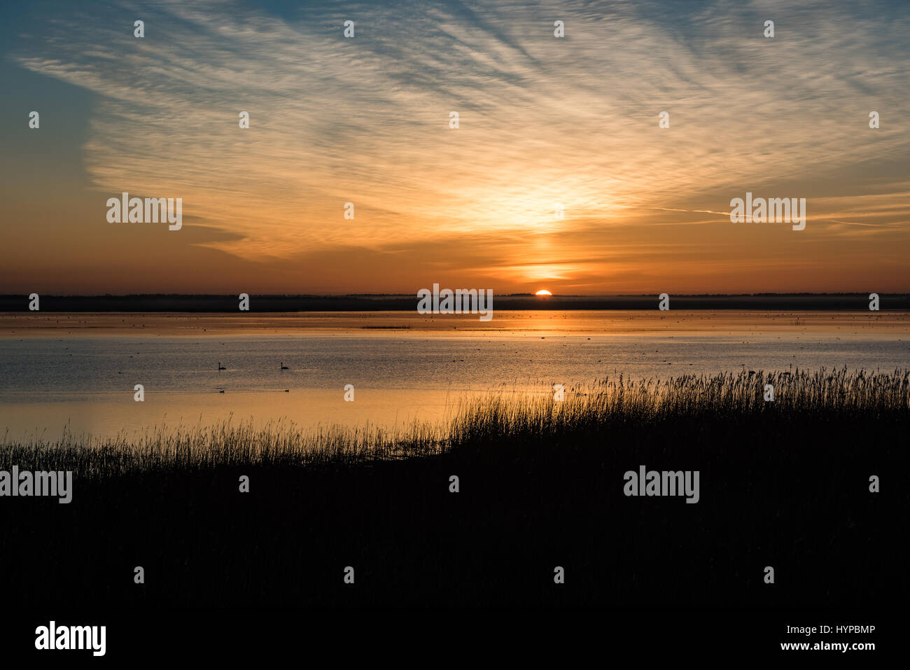 beautiful sunrise over country lake with orange clouds and reflections ...