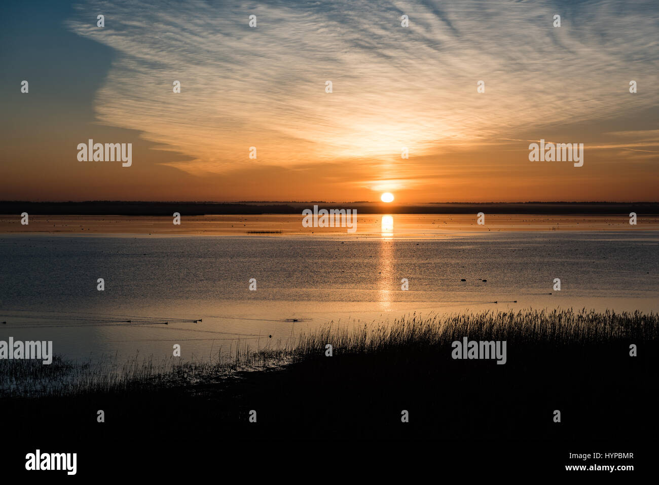 beautiful sunrise over country lake with orange clouds and reflections ...