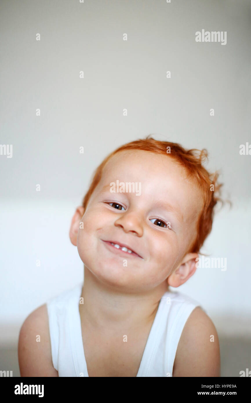 Portrait of a red-haired little boy wearing a tank top smilling ...