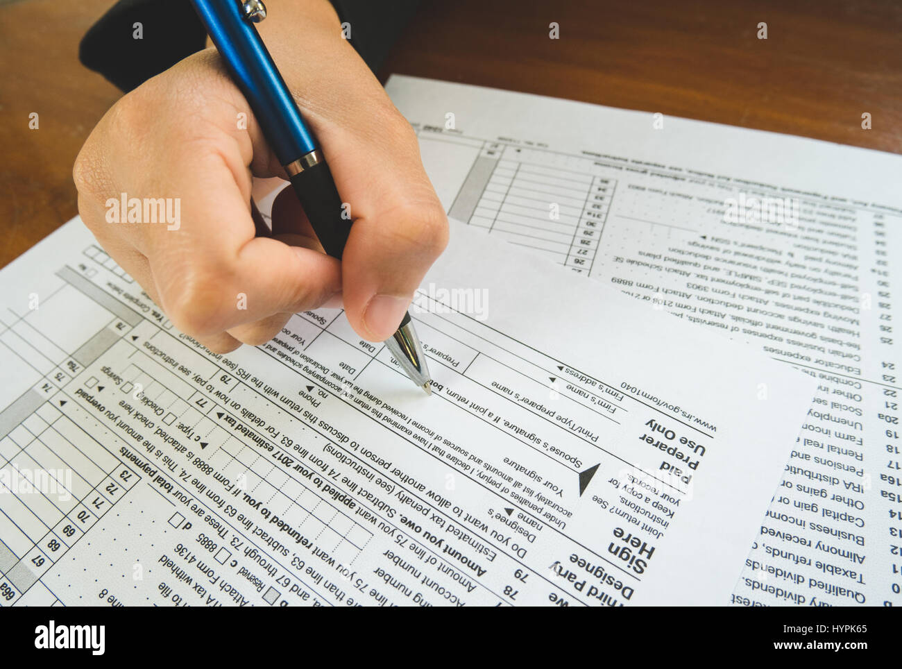 Hand hold pen on sign point on the tax forms paper in business concept ...