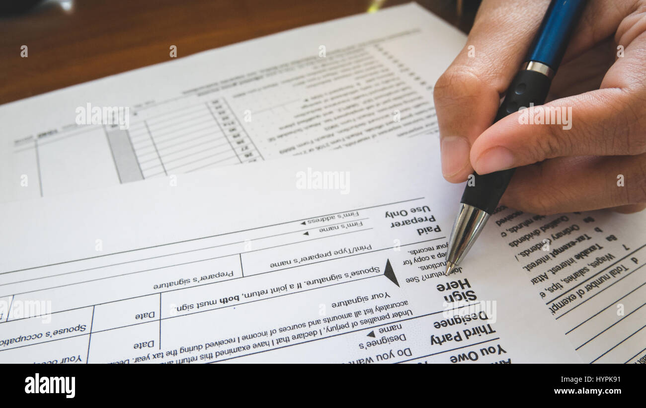 Hand hold pen on sign point on the tax forms paper in business concept ...