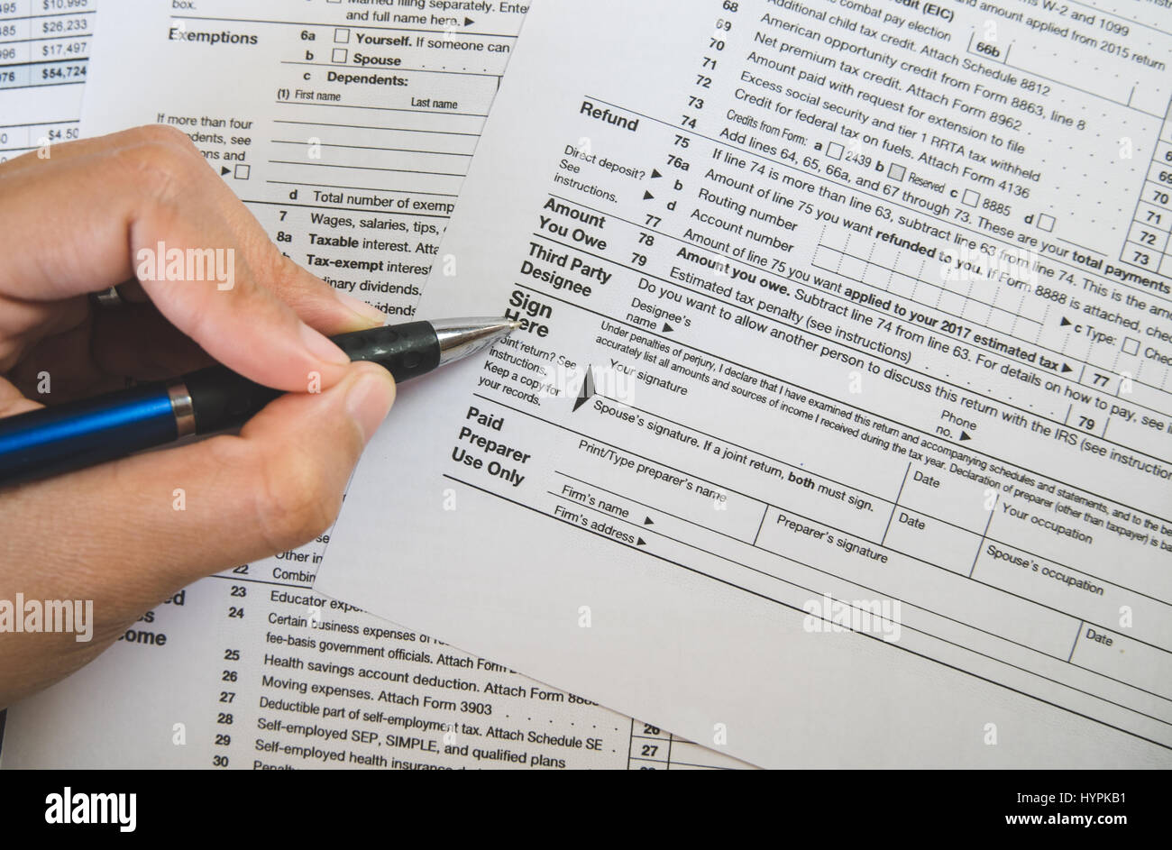 Hand hold pen on sign point on the tax forms paper in business concept ...