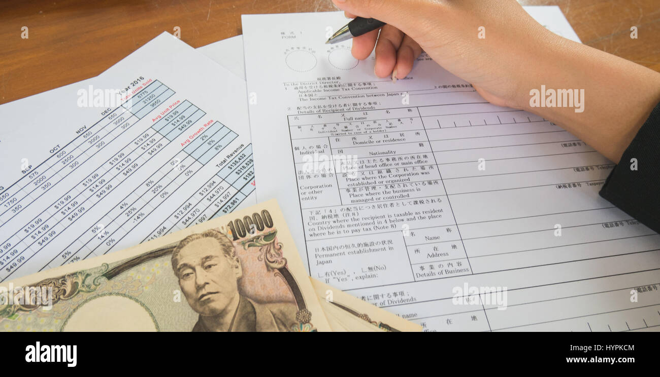 Woman hand hold pen fill in the details on the tax forms paper with yen ...