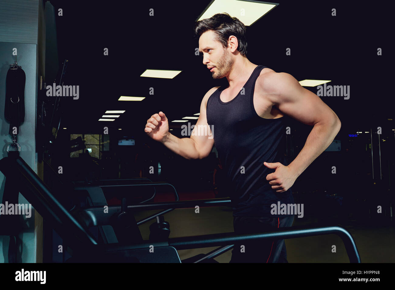Man athlete runs jogging on a treadmill in dark gym Stock Photo - Alamy