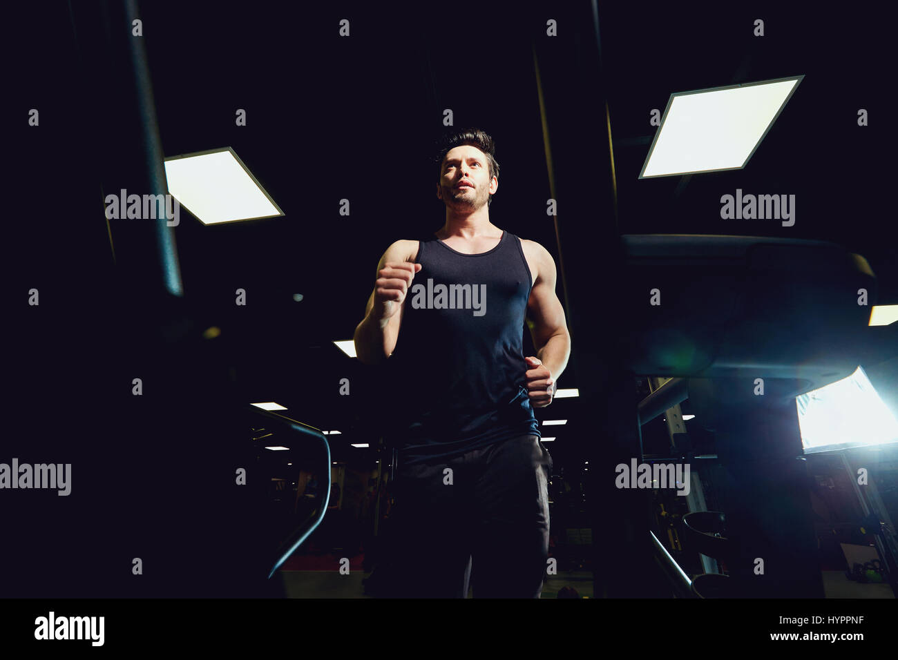 Man athlete runs jogging on a treadmill in dark gym Stock Photo - Alamy