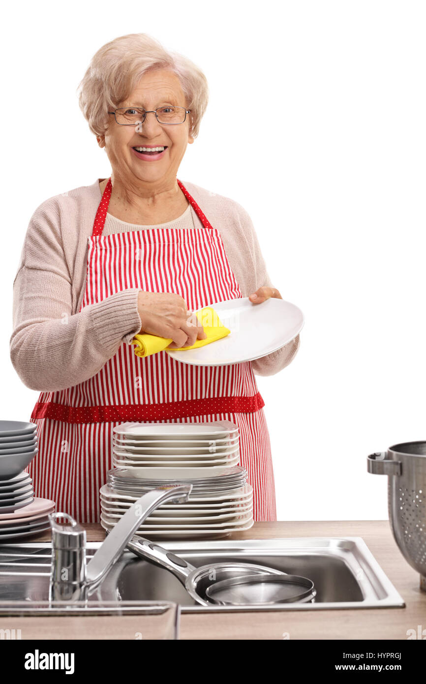 Cheerful elderly woman wiping plates and looking at the camera isolated ...