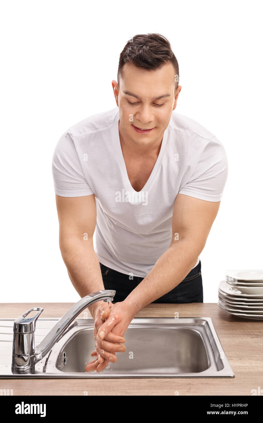 Young man washing his hands in a sink isolated on white background ...