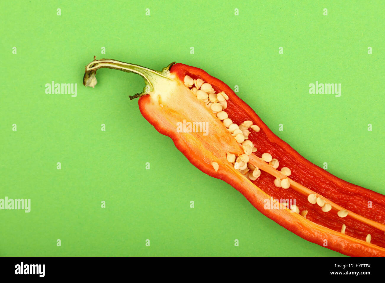 One cut half of fresh red hot chili pepper on green paper background ...