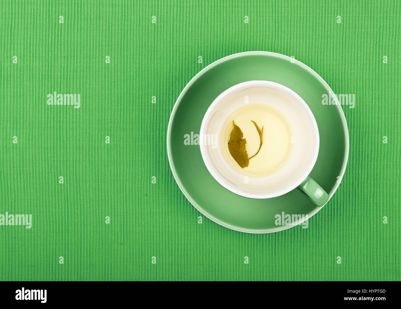 Empty cup of clear green tea with leaf on bottom at saucer over green ...