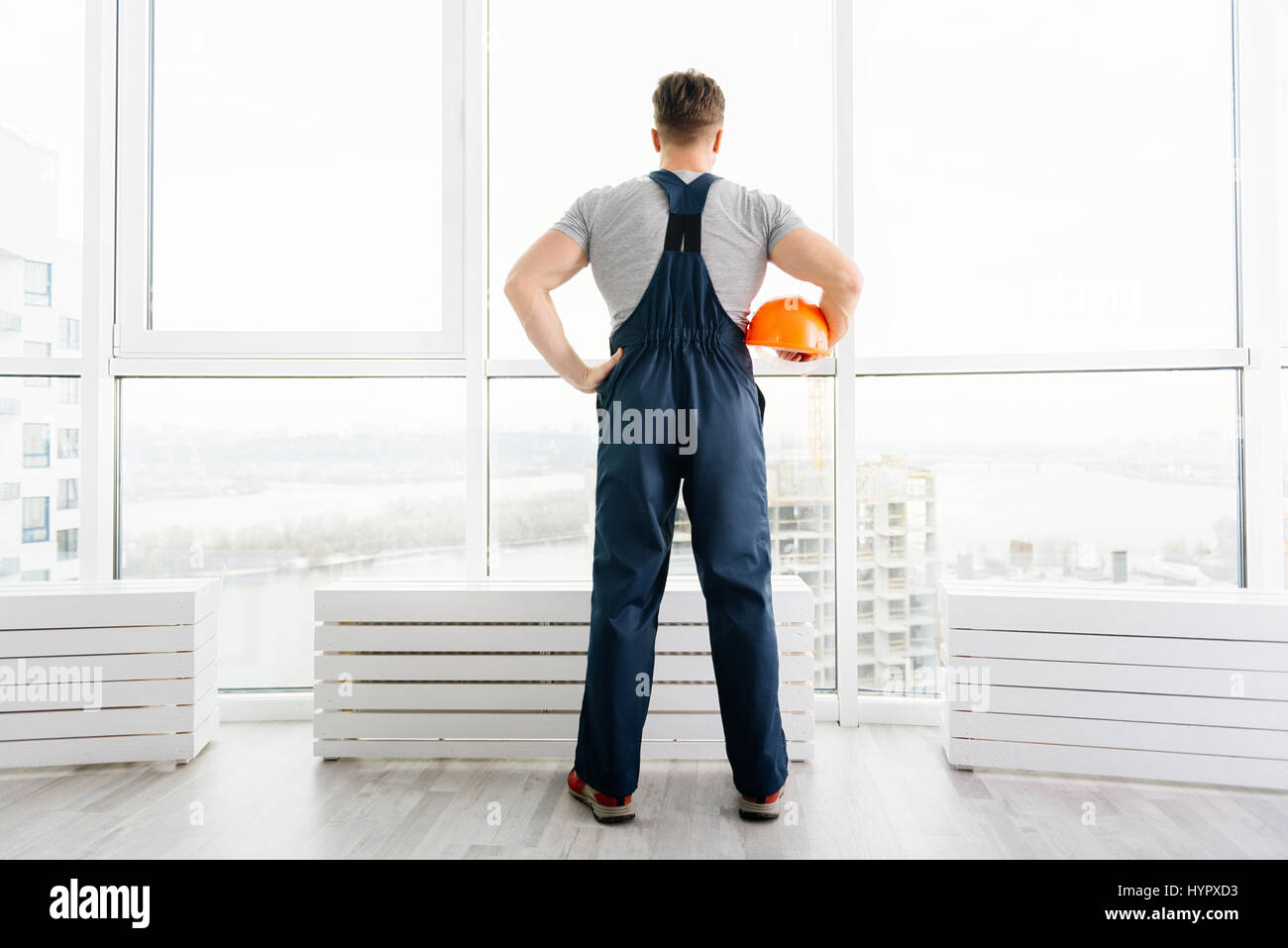 Rear view of construction engineer standing near big window Stock Photo ...