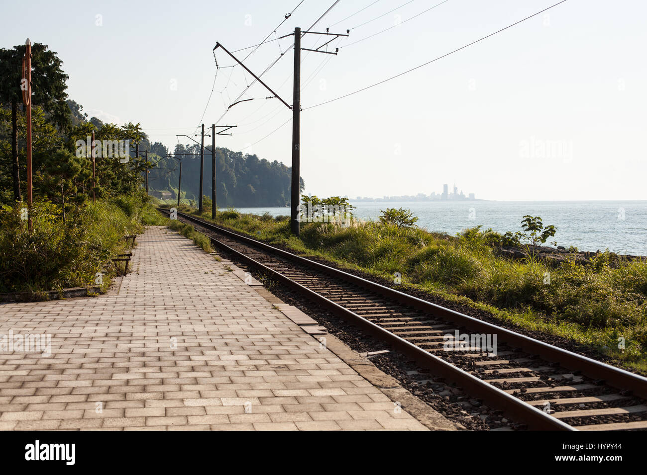 Train rail near the sea with electric power line Stock Photo - Alamy