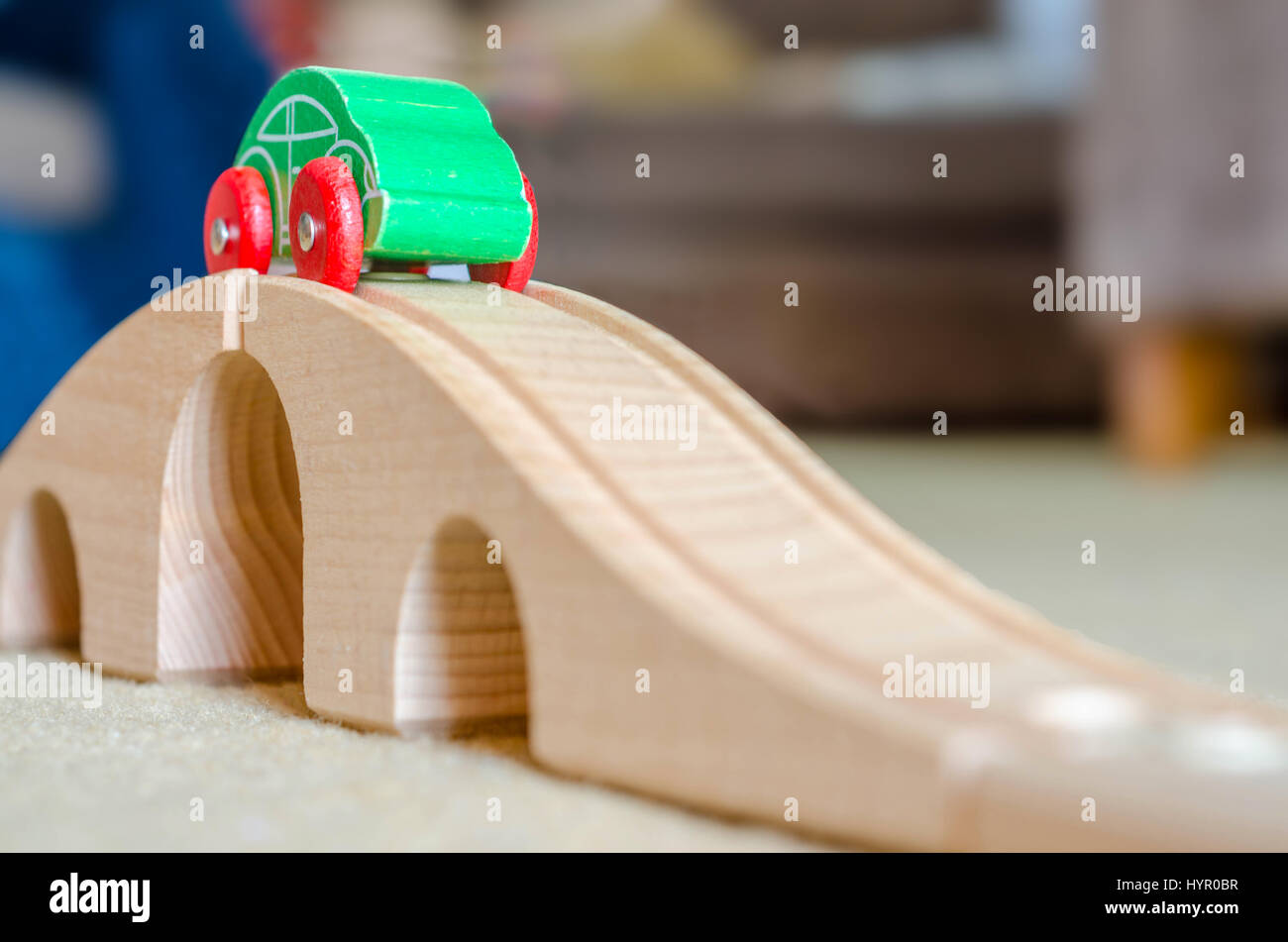 A toy wooden car on top of a toy wooden bridge. The car runs a long a ...