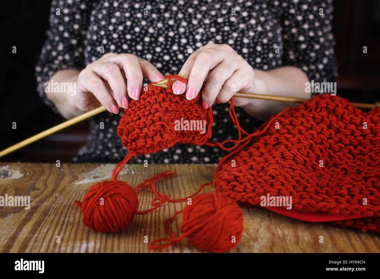 elderly woman is engaged in knitting warm sweaters for her grand Stock ...