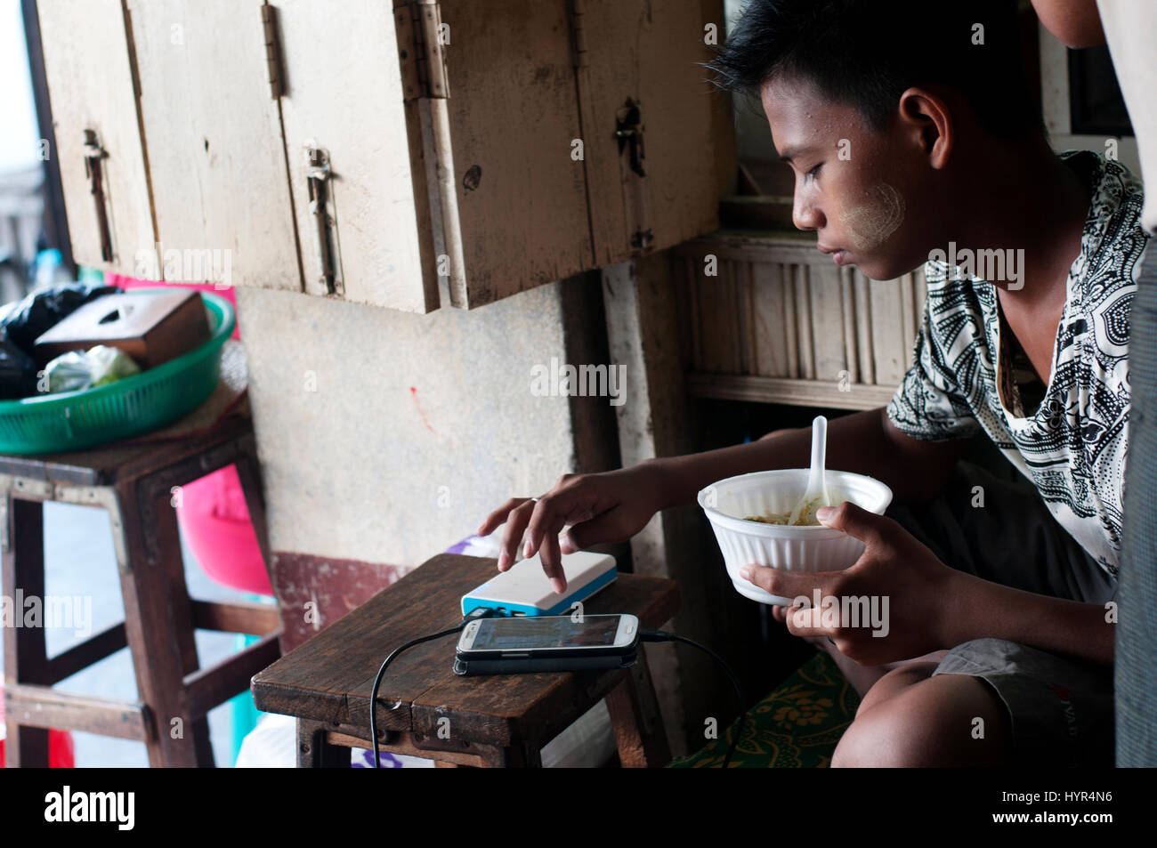 Myanmar (Burma). Yangon. A young man working in the market checks his ...