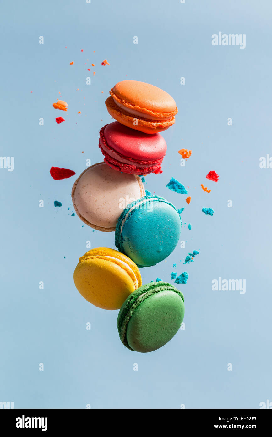 Different types of macaroons in motion falling on blue background ...