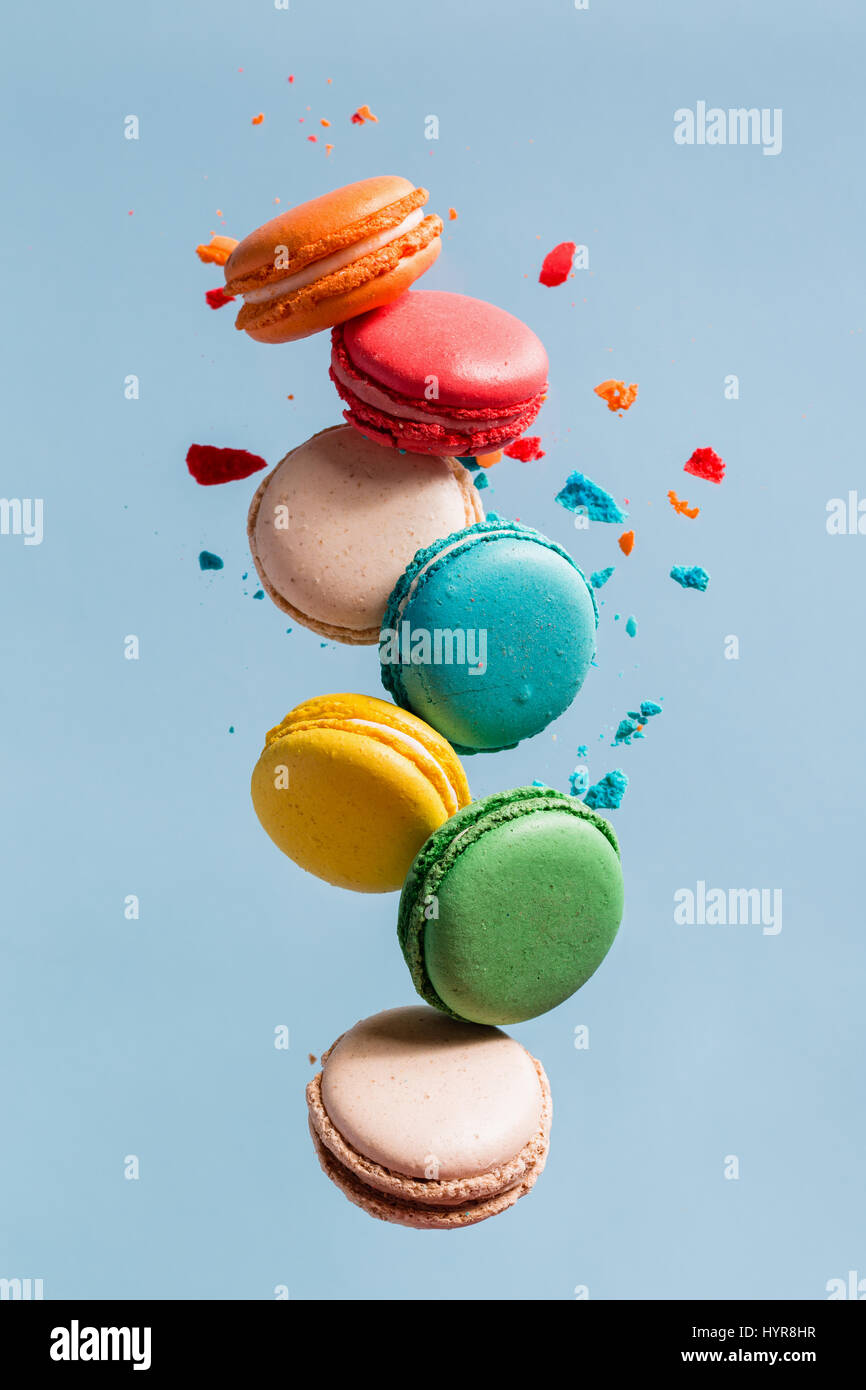 Different types of macaroons in motion falling on light blue background ...