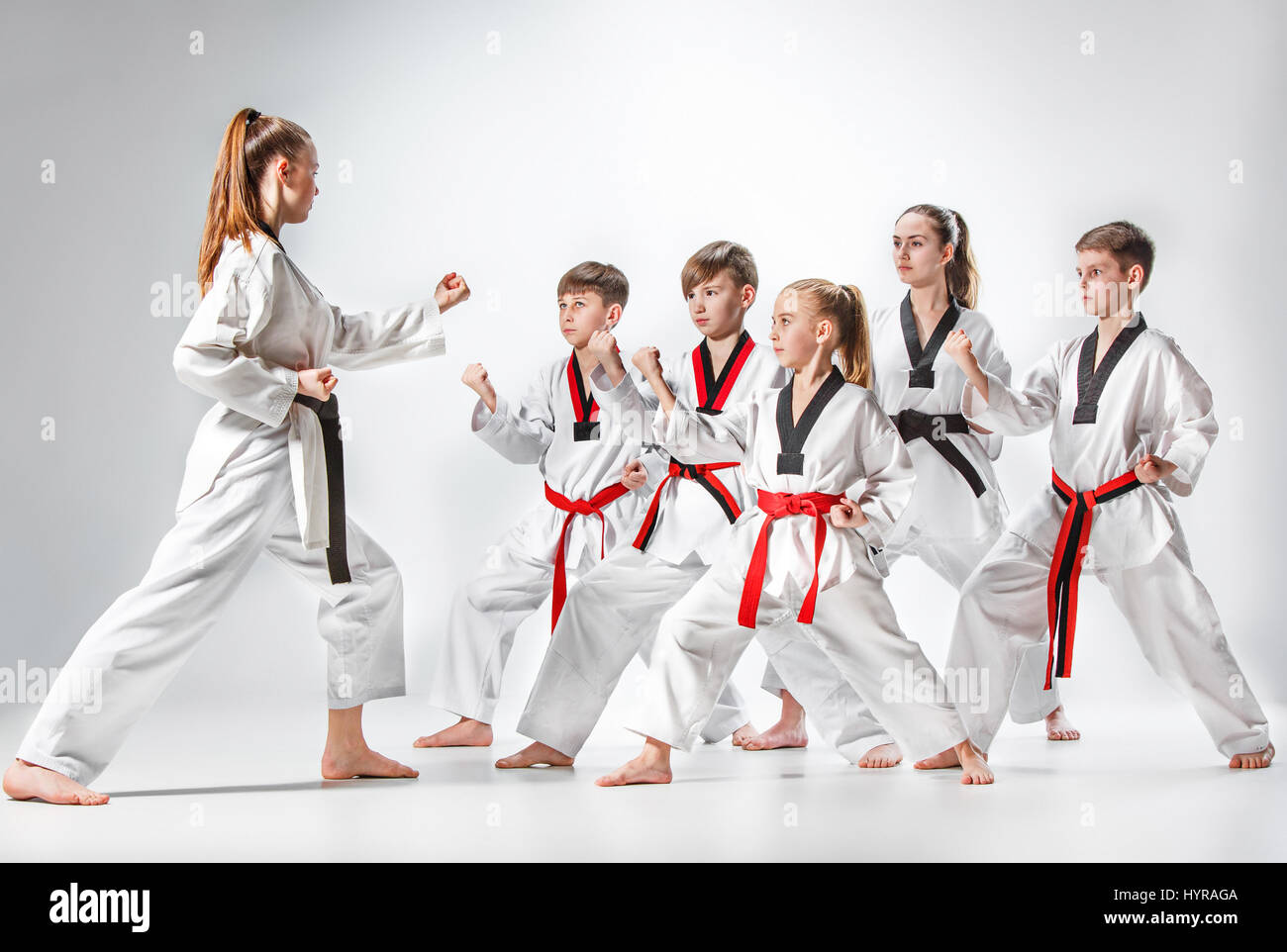 The studio shot of group of kids training karate martial arts on gray ...