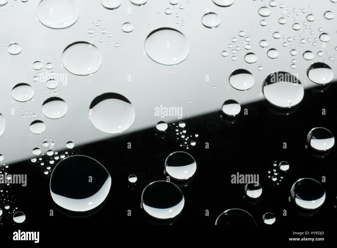 Round shaped water droplets on glass surface. Dark background behind ...