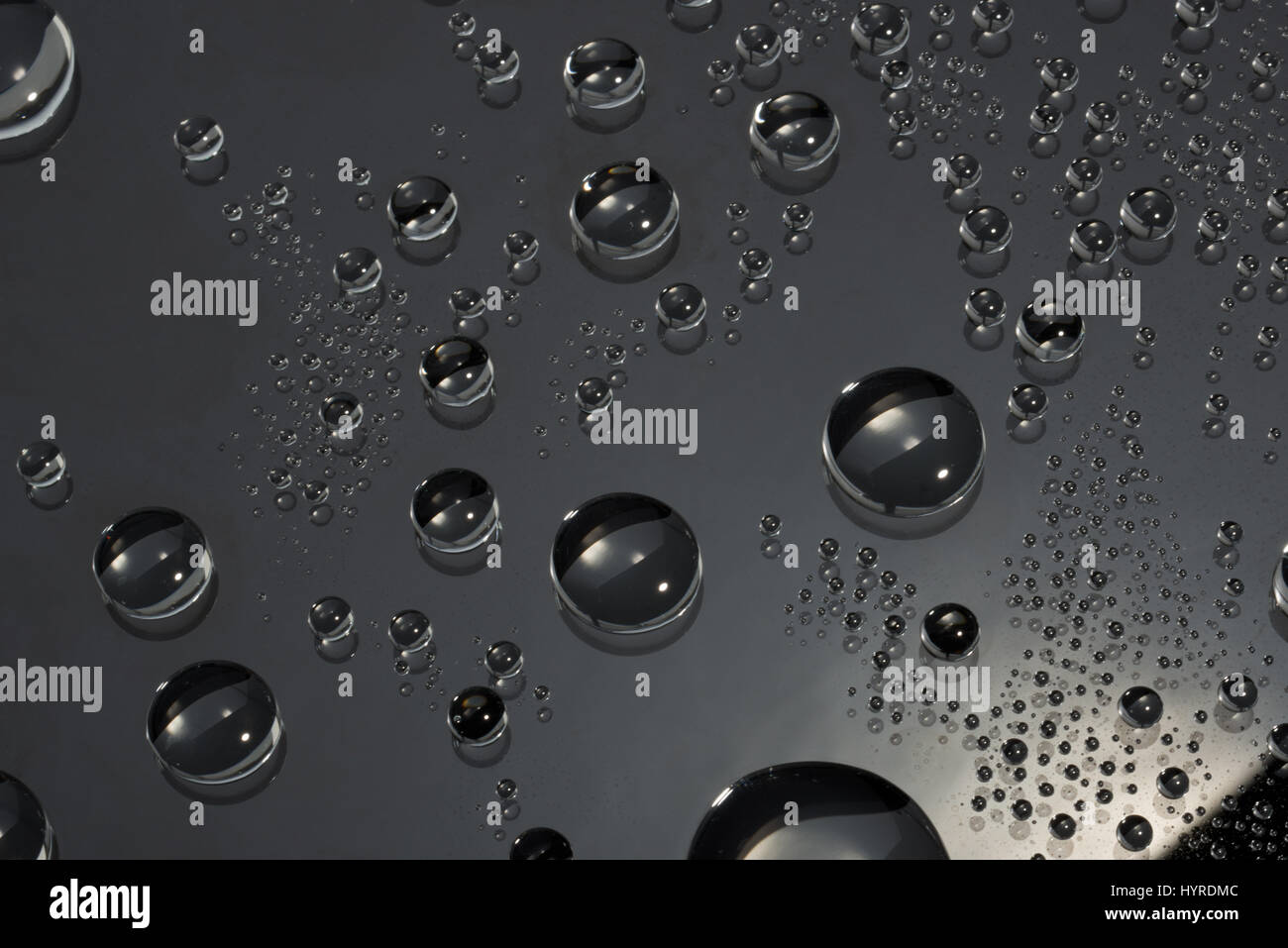 Round shaped water droplets on glass surface. Dark background behind ...