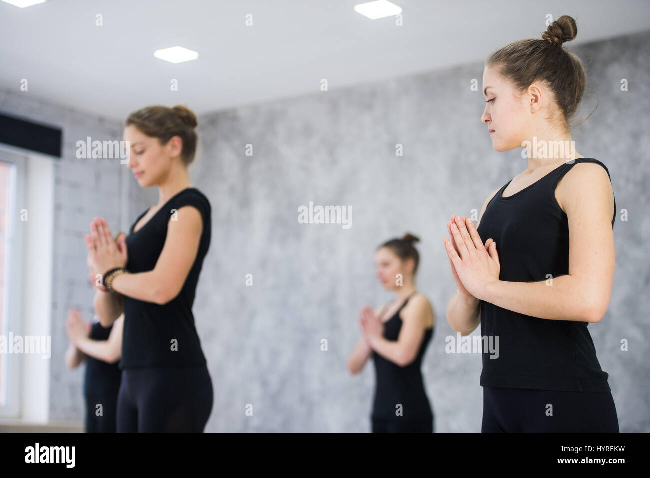 Female trainer with class standing in namaste pose at yoga class Stock ...