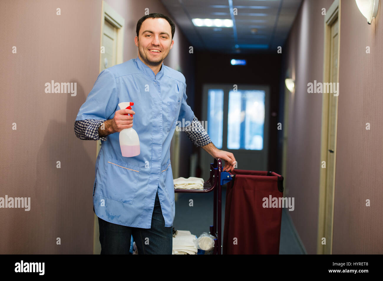Man cleaning hotel hall wearing blue coat Stock Photo - Alamy