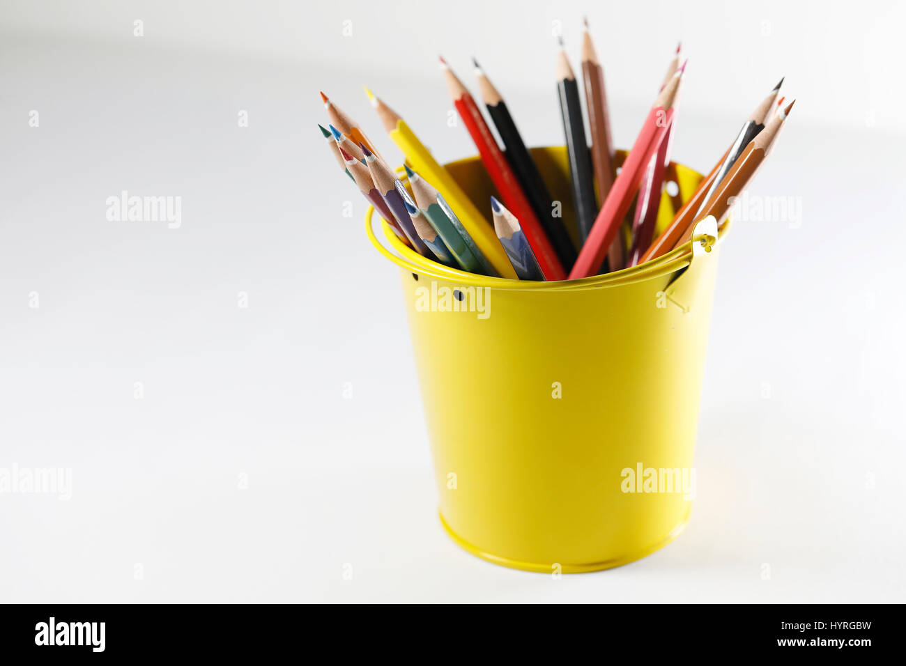 Color pencils in yellow bucket isolated on white background Stock Photo ...