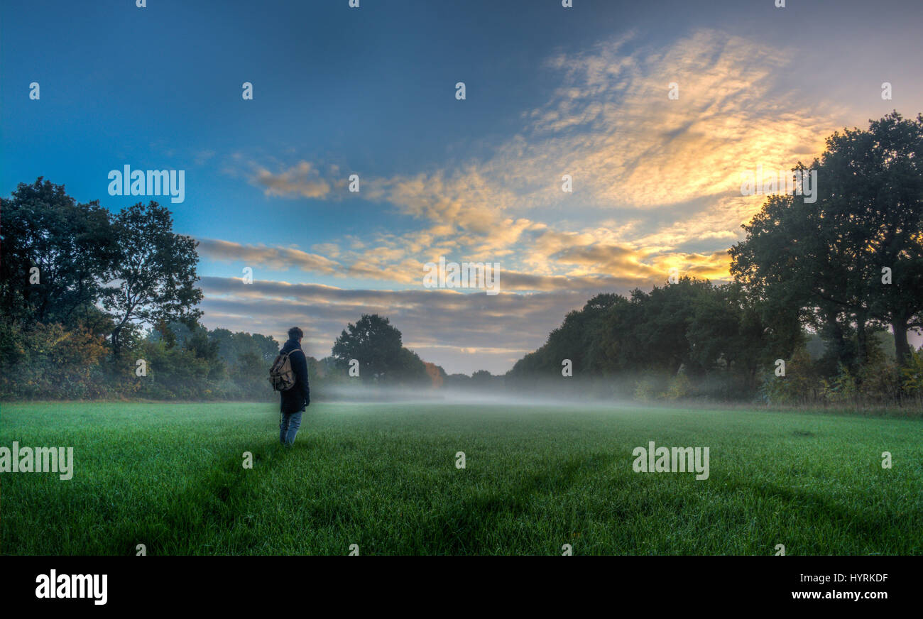 Lonely wanderer in a misty field Stock Photo - Alamy