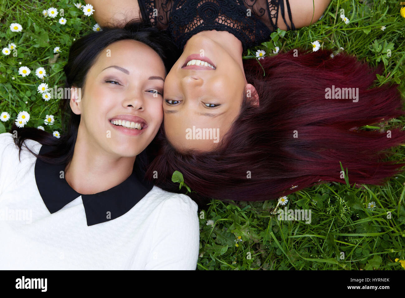 Portrait of a two happy sisters lying on grass outdoors Stock Photo - Alamy
