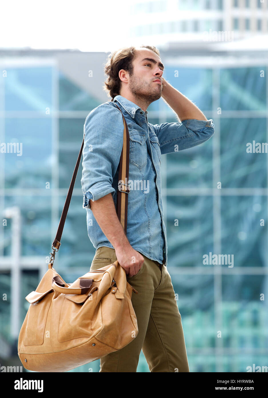 Portrait of a male fashion model posing with leather bag outdoors Stock ...