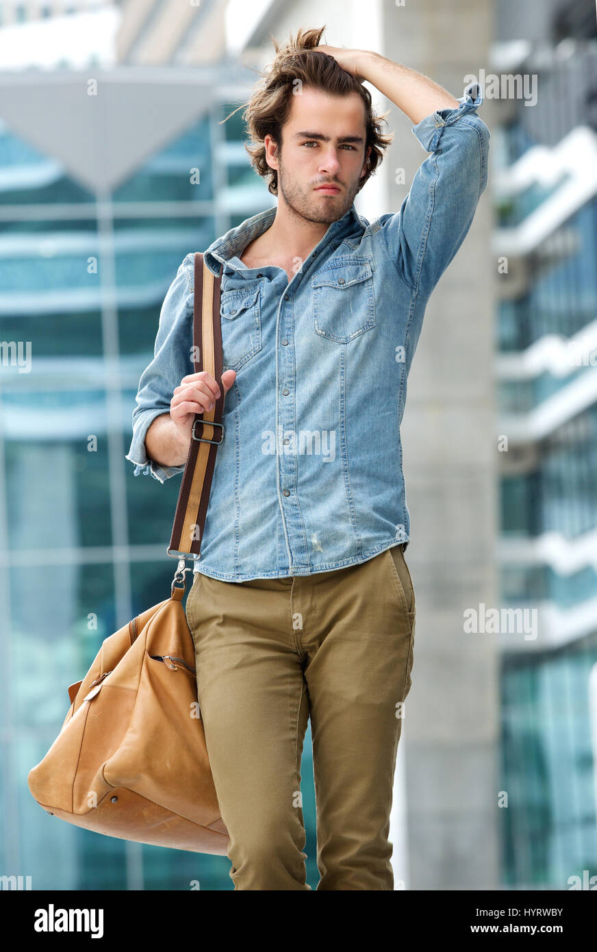 Portrait of a male model posing with travel bag outdoors Stock Photo ...
